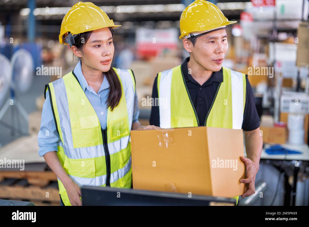 Staff working in large depot storage warehouse trainee check packing ...