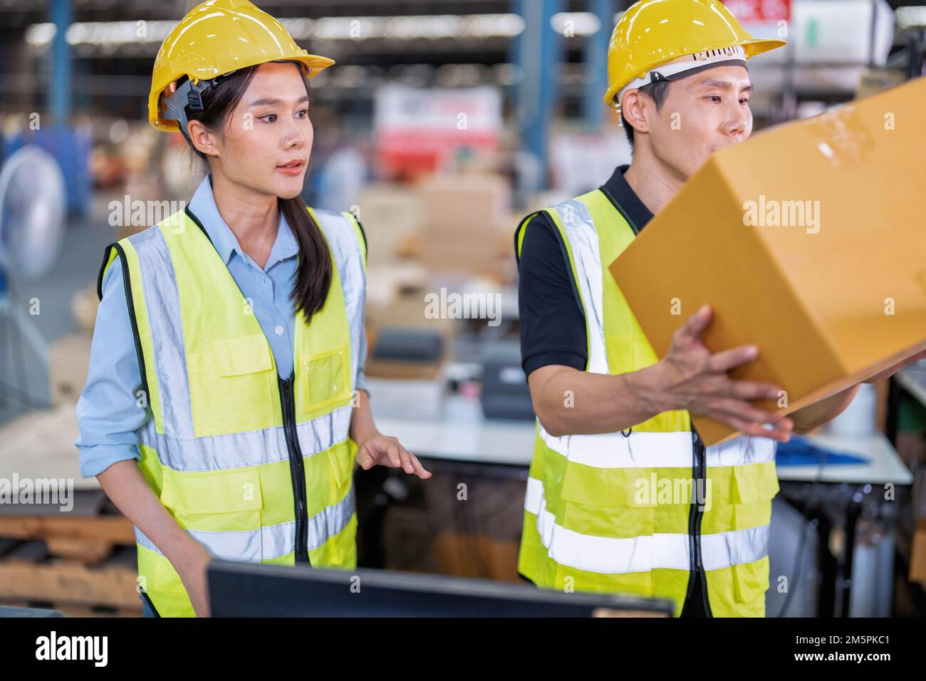 Staff working in large depot storage warehouse trainee check packing ...