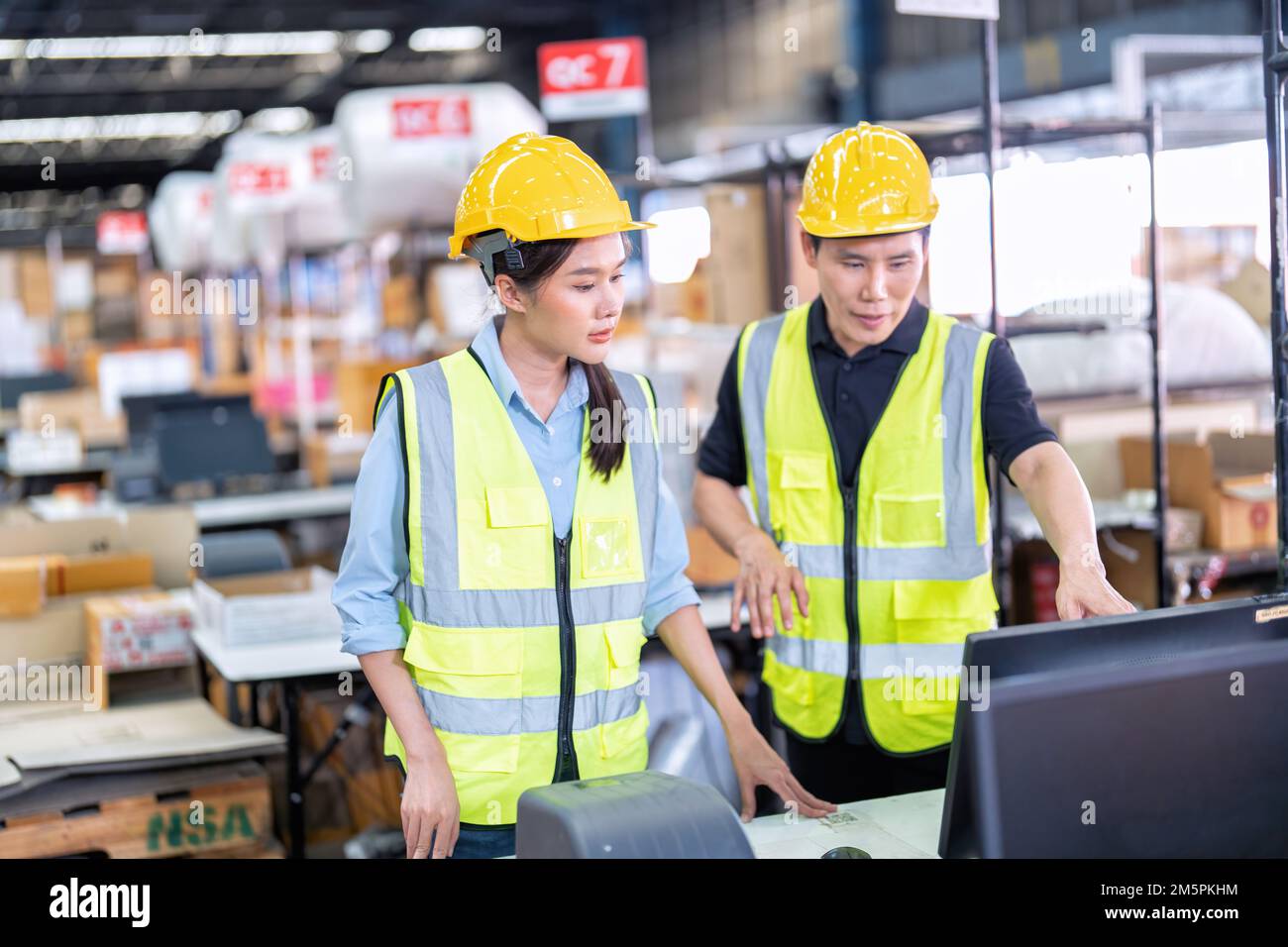 Staff working in large depot storage warehouse trainee check packing ...