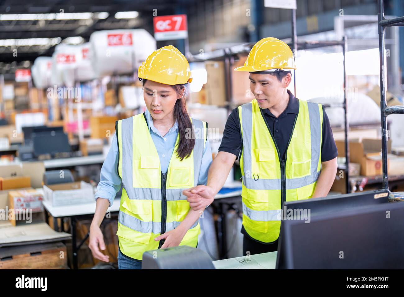 Staff working in large depot storage warehouse trainee check packing ...
