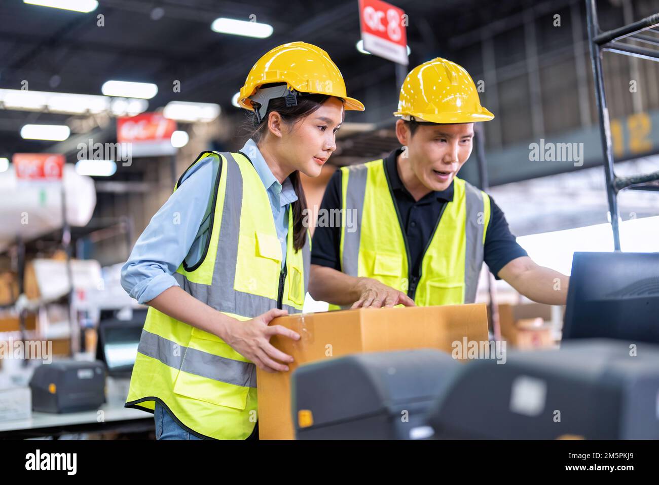 Staff working in large depot storage warehouse trainee check packing box and scan at cashier ...