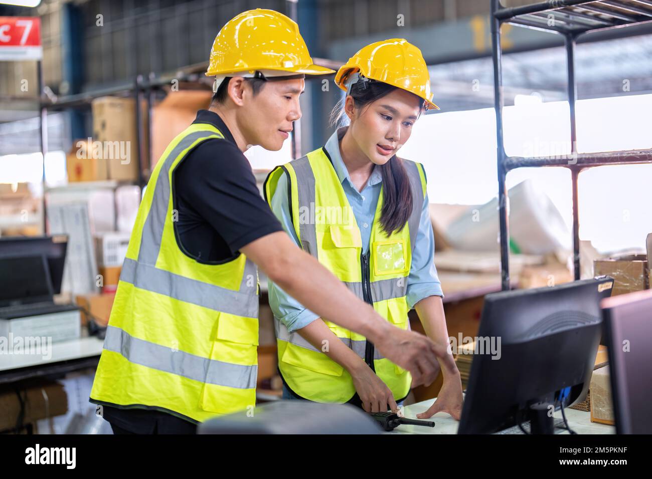 Staff working in large depot storage warehouse trainee check packing box and scan at cashier ...