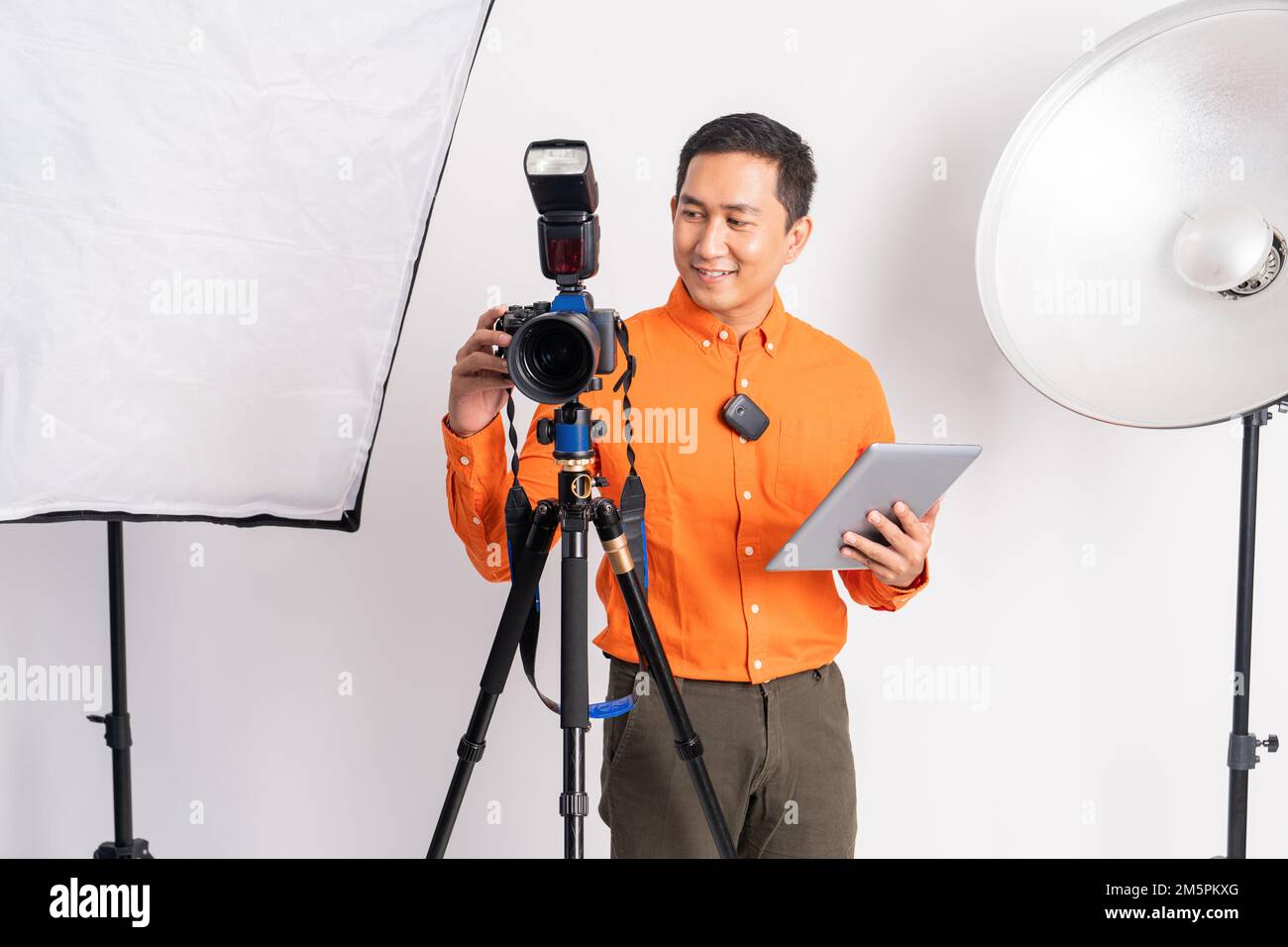 vlogger standing setting camera and holding tablet with lighting ...