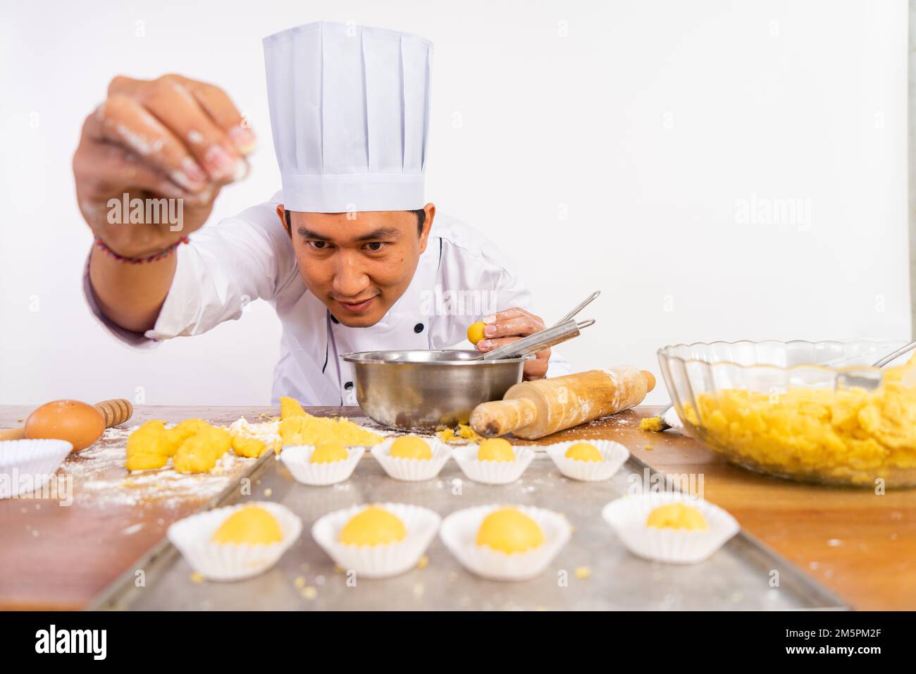 male chef carefully sprinkles topping on cake on tray Stock Photo - Alamy