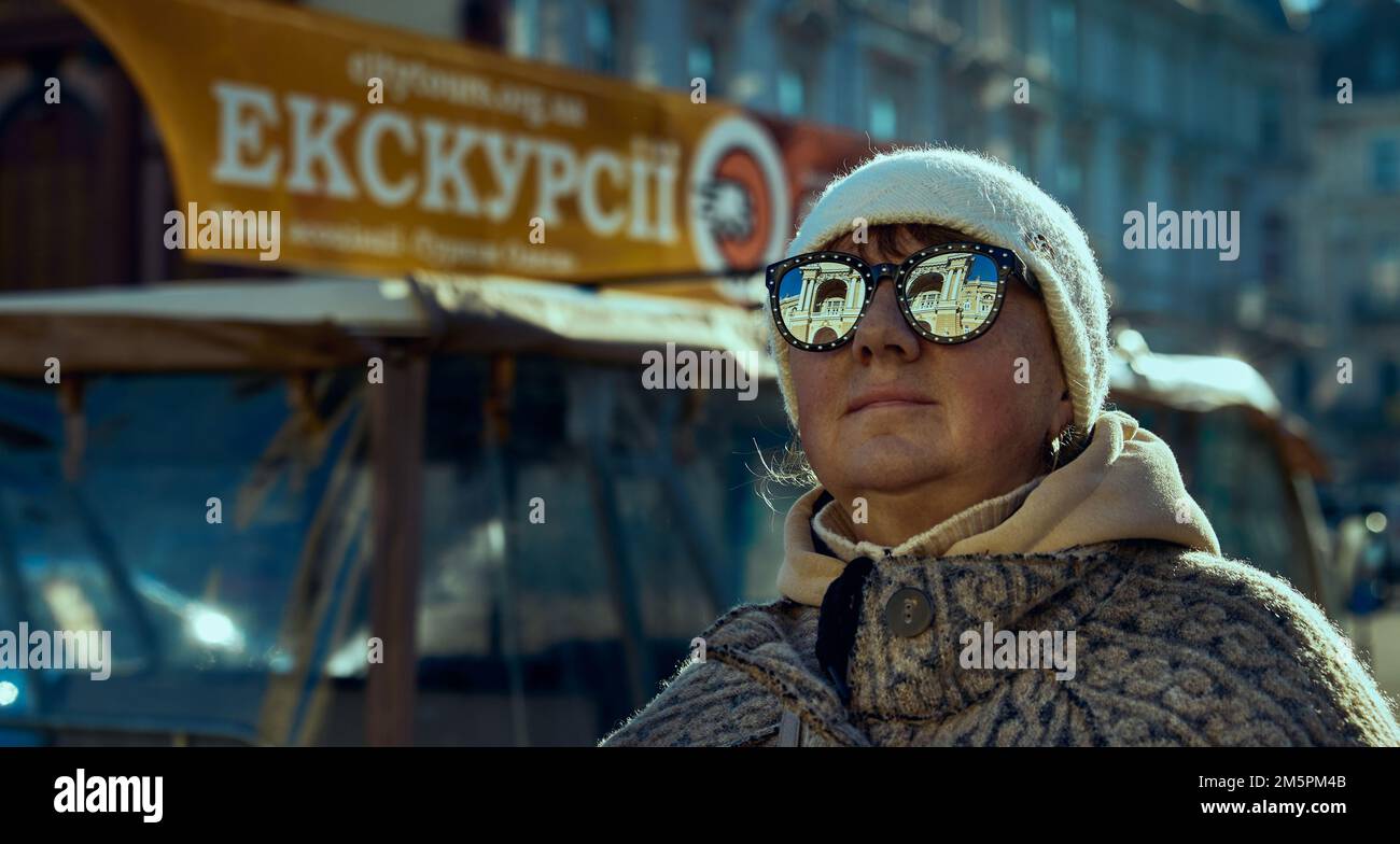 Portrait of a pretty woman whose sun glasses reflect the opera house ...