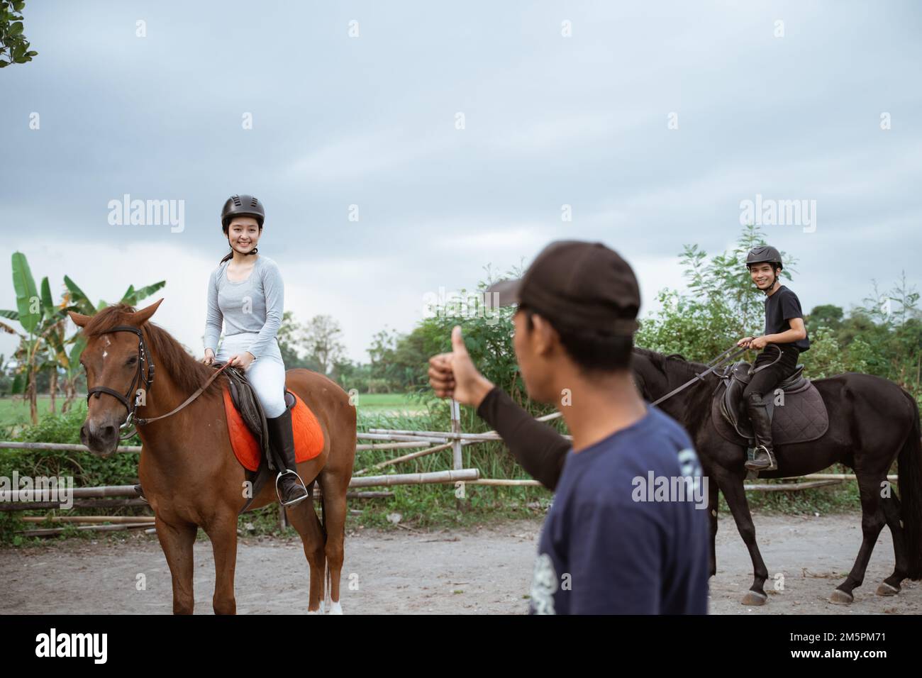 two equestrian athletes riding horses given thumbs up by coach Stock ...