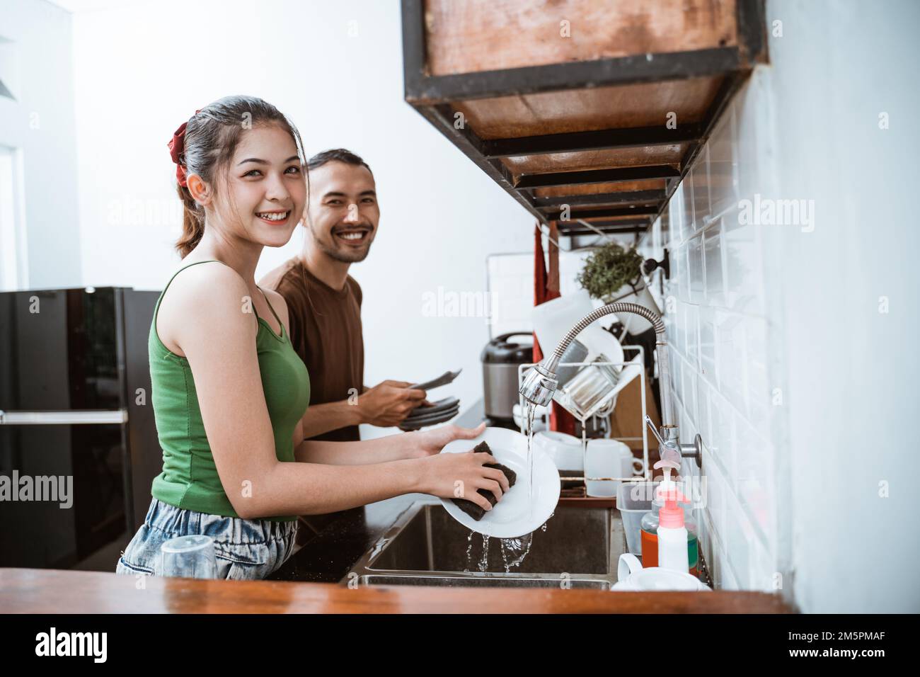 young asian woman and man smiling while washing dishes together Stock ...