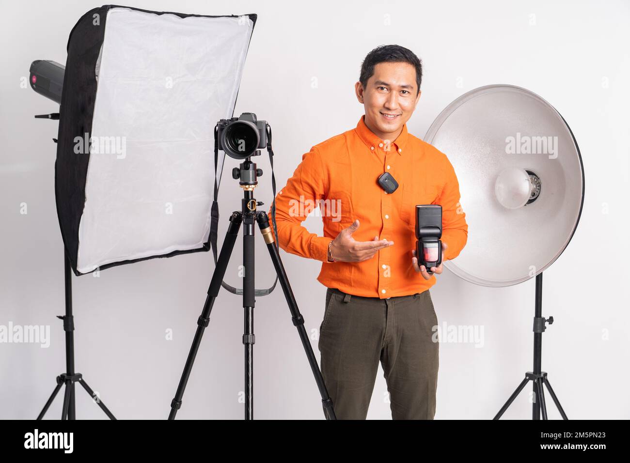 young man holding camera flash with hand gesture pointing Stock Photo ...