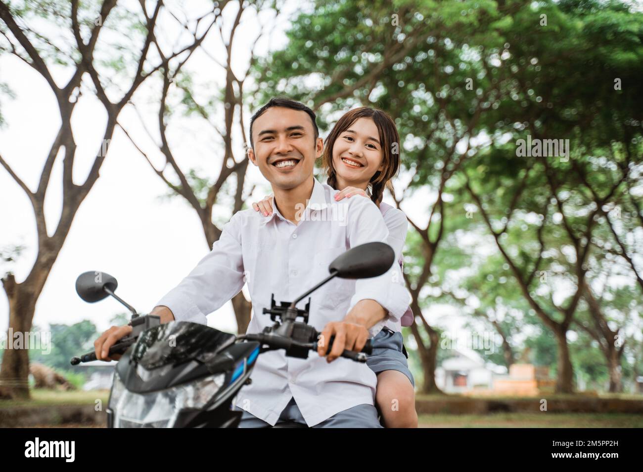 couple of students riding a motorcycle without a helmet Stock Photo - Alamy