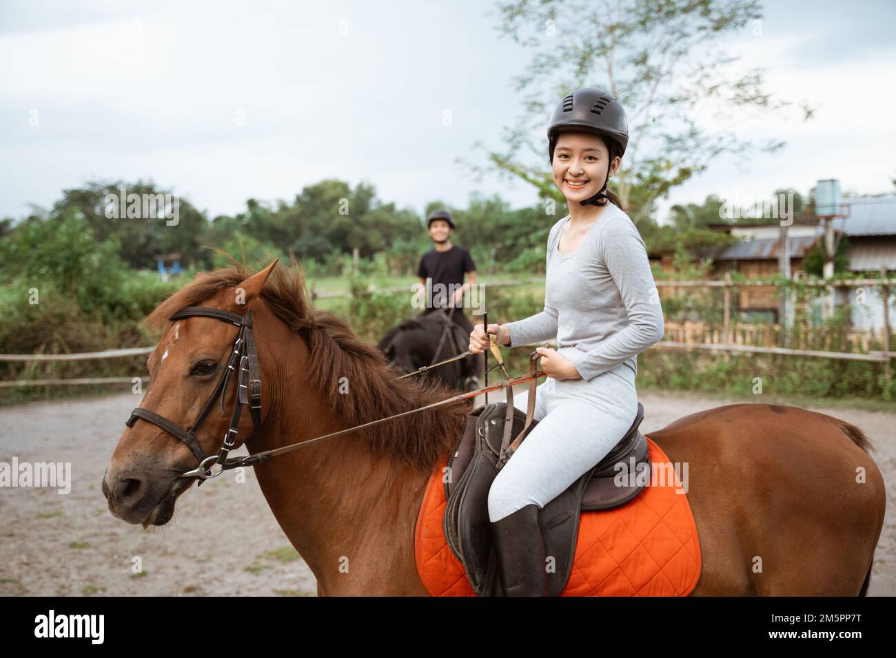 female athlete riding horse to train with male athlete Stock Photo - Alamy