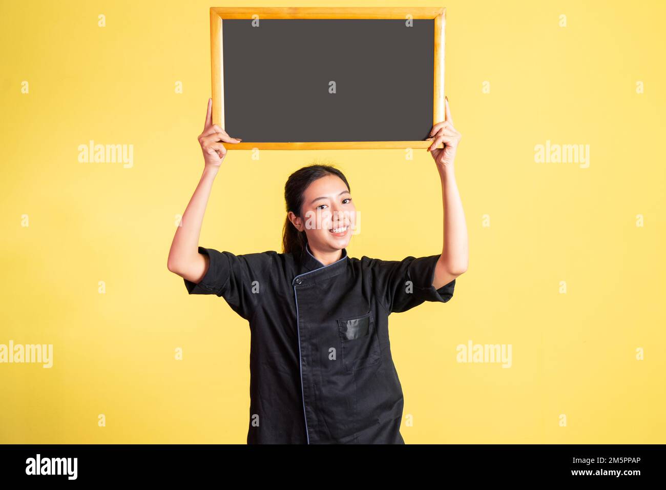 smiling asian female chef lifting and showing blank blackboard Stock ...