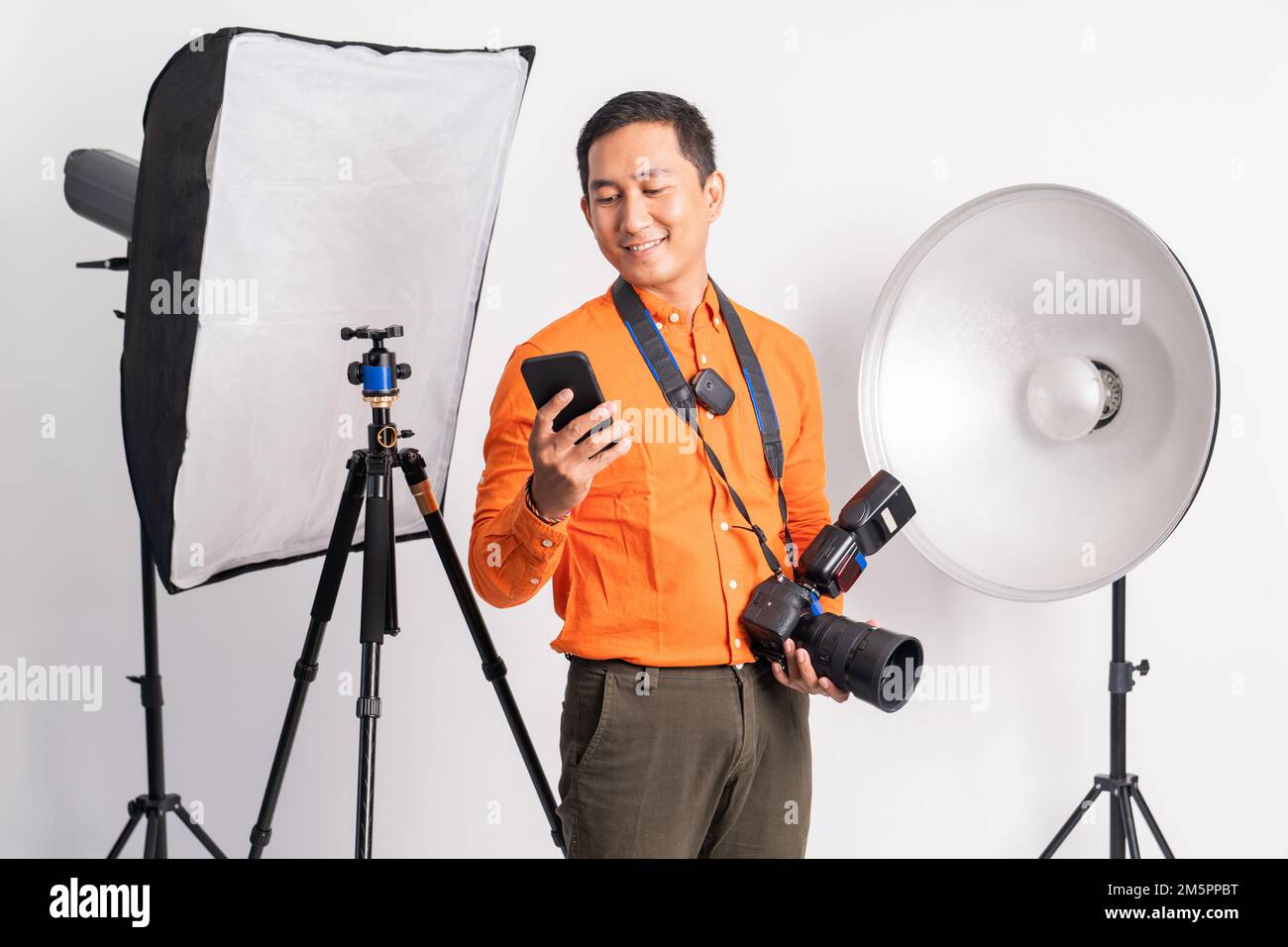 male vlogger standing using mobile phone while holding camera Stock ...