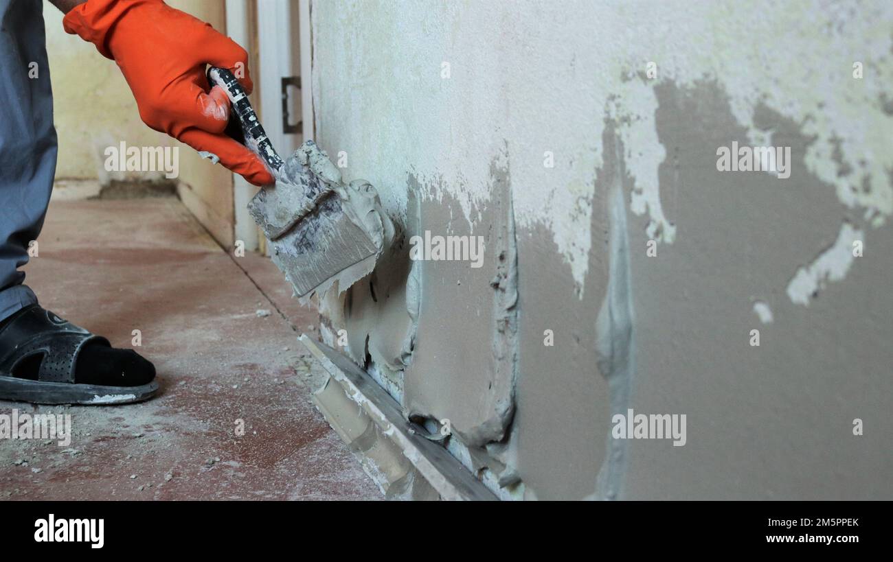 leveling a room wall with a thick layer of plastic putty using a ...