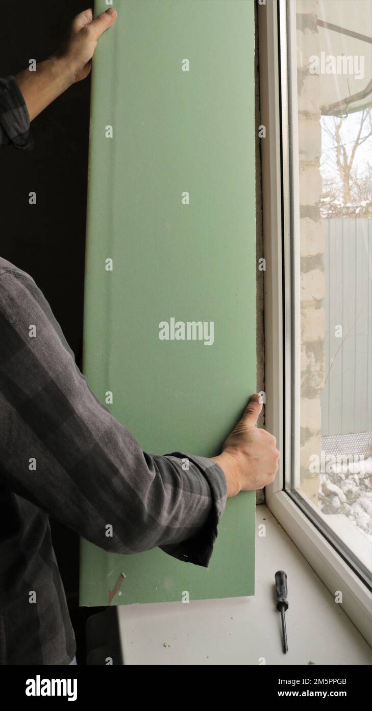 installing a chipboard sheet on the slope of the window opening in the ...