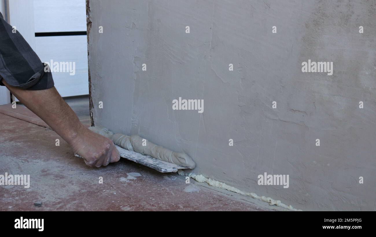 plastering a room wall with an elastic mortar using a wide spatula ...