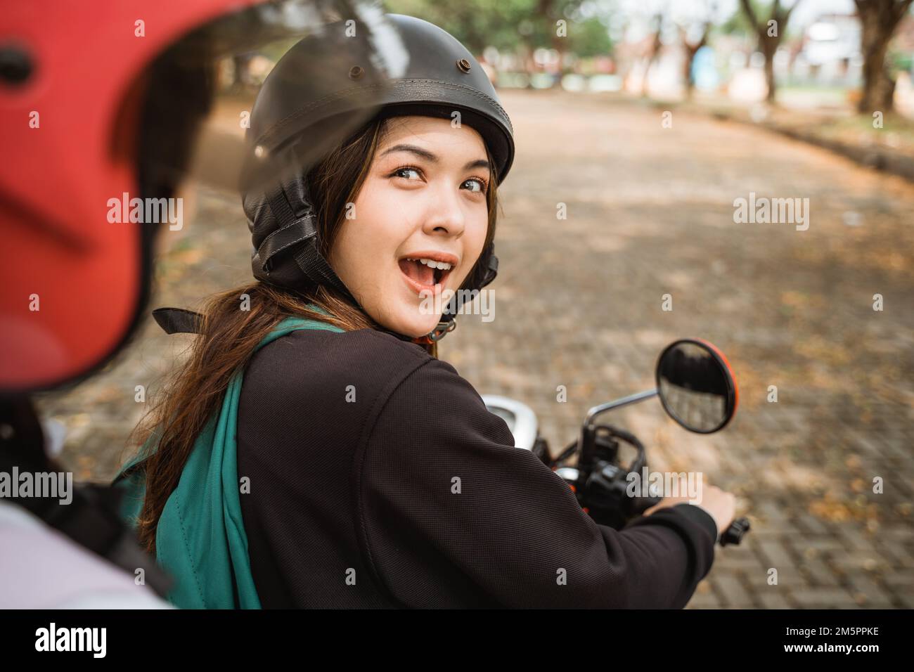 High school students looking back chatting while riding motorbikes ...
