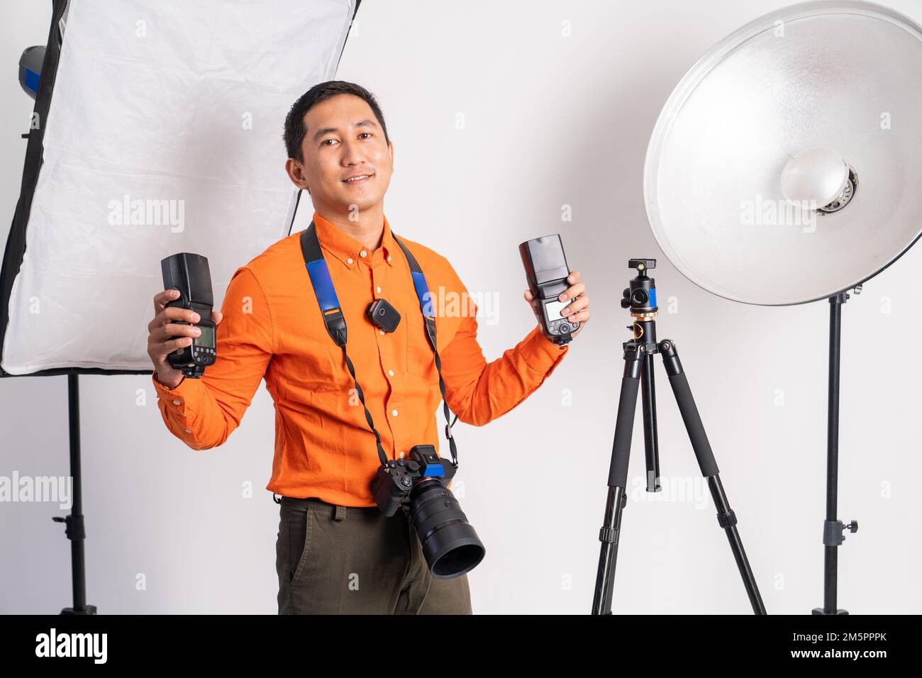 smiling photographer holding two flashes with a camera Stock Photo - Alamy