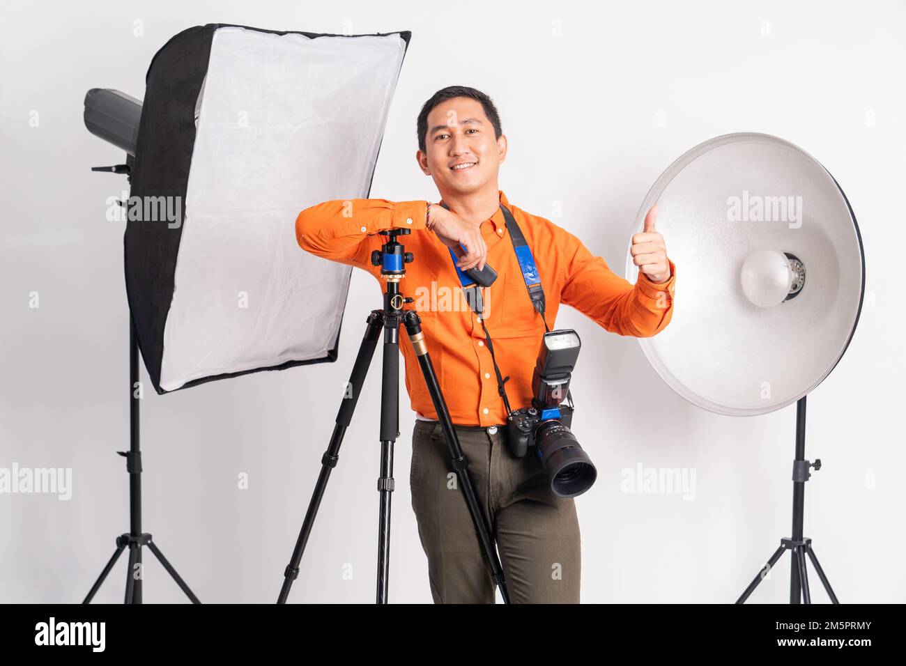 smiling man leaning on tripod carrying camera with thumbs up Stock ...