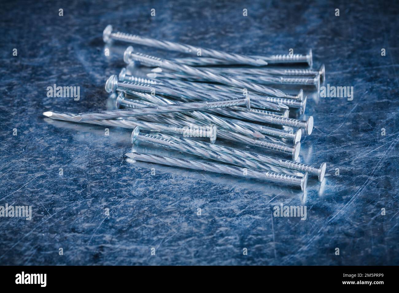 Long stainless construction nails on scratched metallic background ...