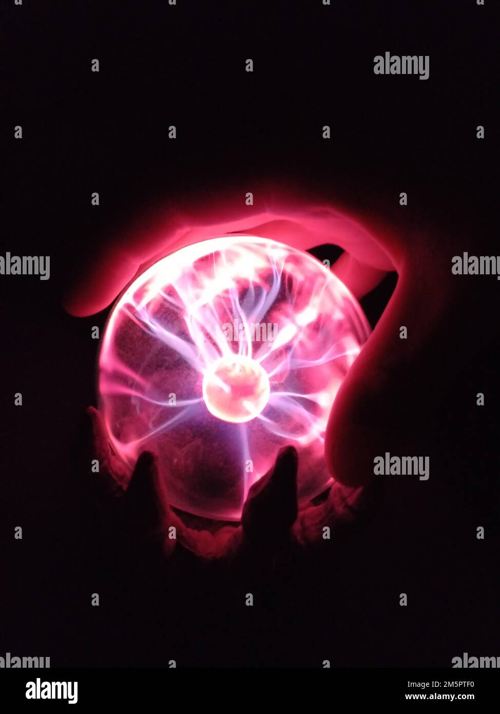 A closeup of a bright plasma globe with a hand touching it Stock Photo ...