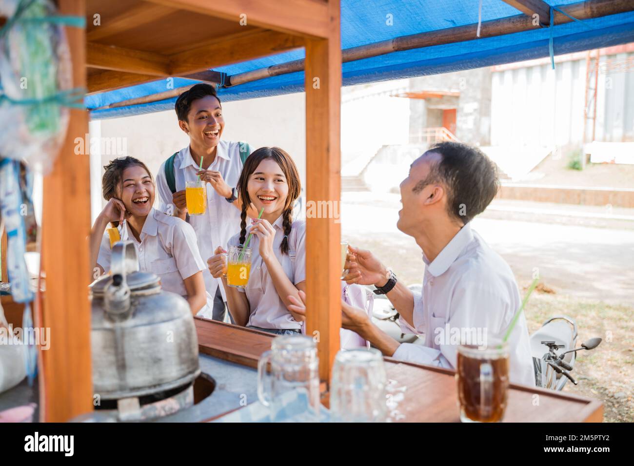 Two boys and two girls students at a cart stall Stock Photo - Alamy