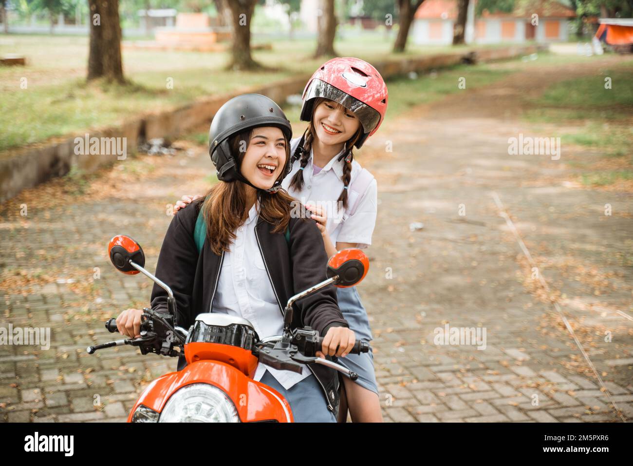 Two friends have fun while riding a motorbike to school Stock Photo - Alamy