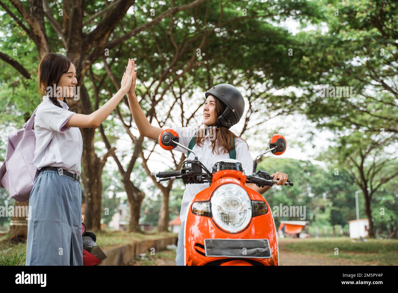 Two student girls clapping hands while taking them home Stock Photo - Alamy
