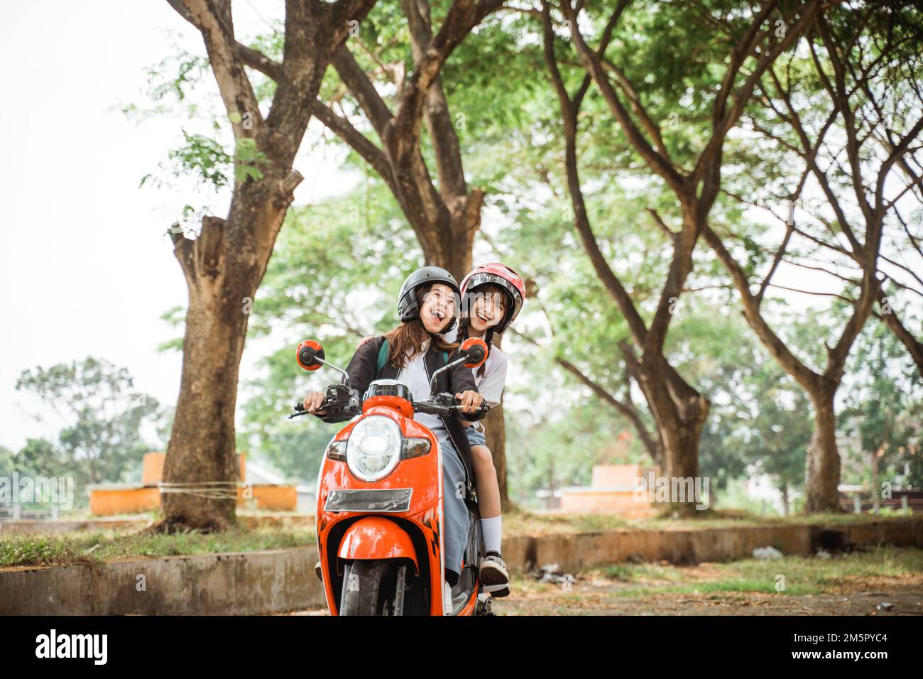 Two student girls enjoy going to school together on motorbike Stock ...