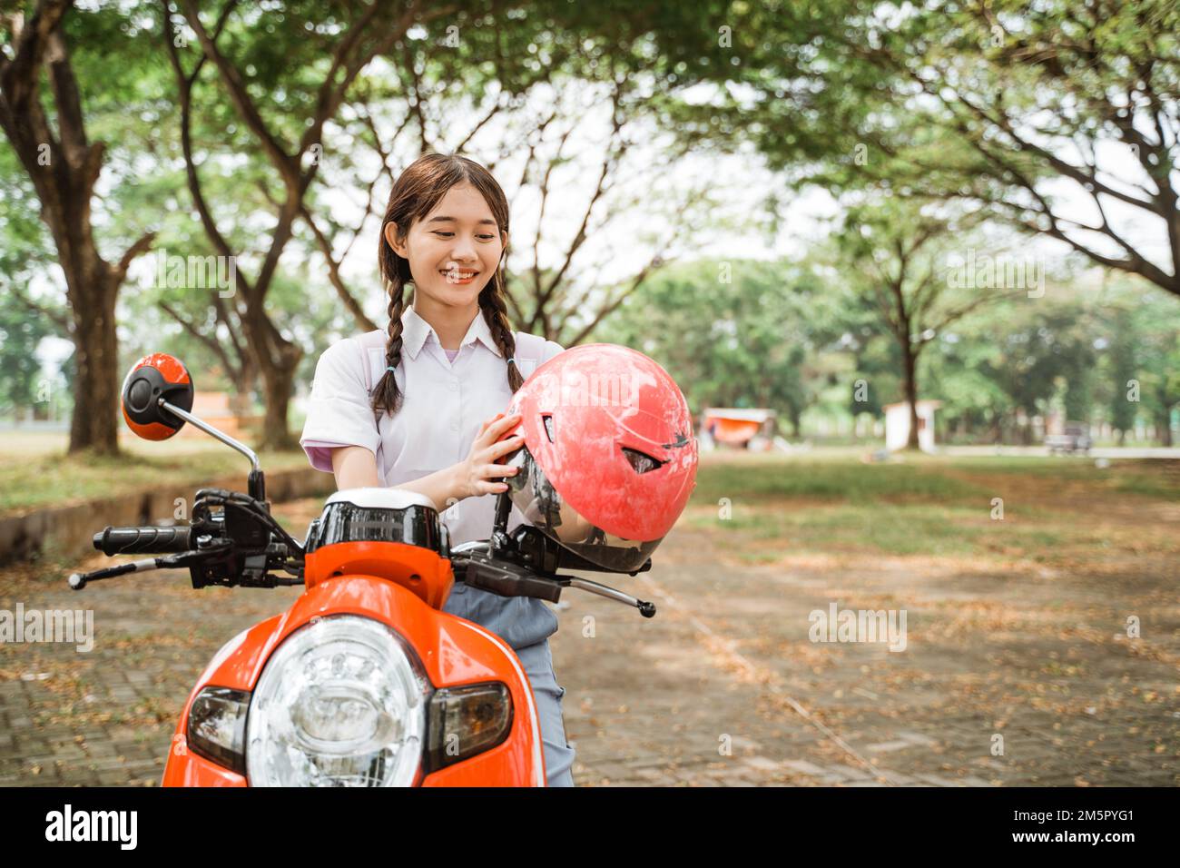Student girl taking off helmet on motorbike with outdoor background ...