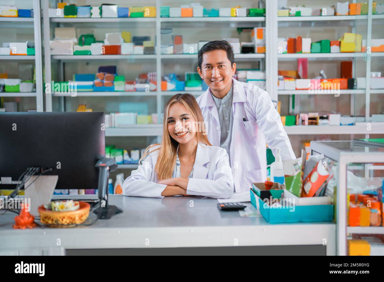 male pharmacist and female pharmacist in uniform working with computer ...