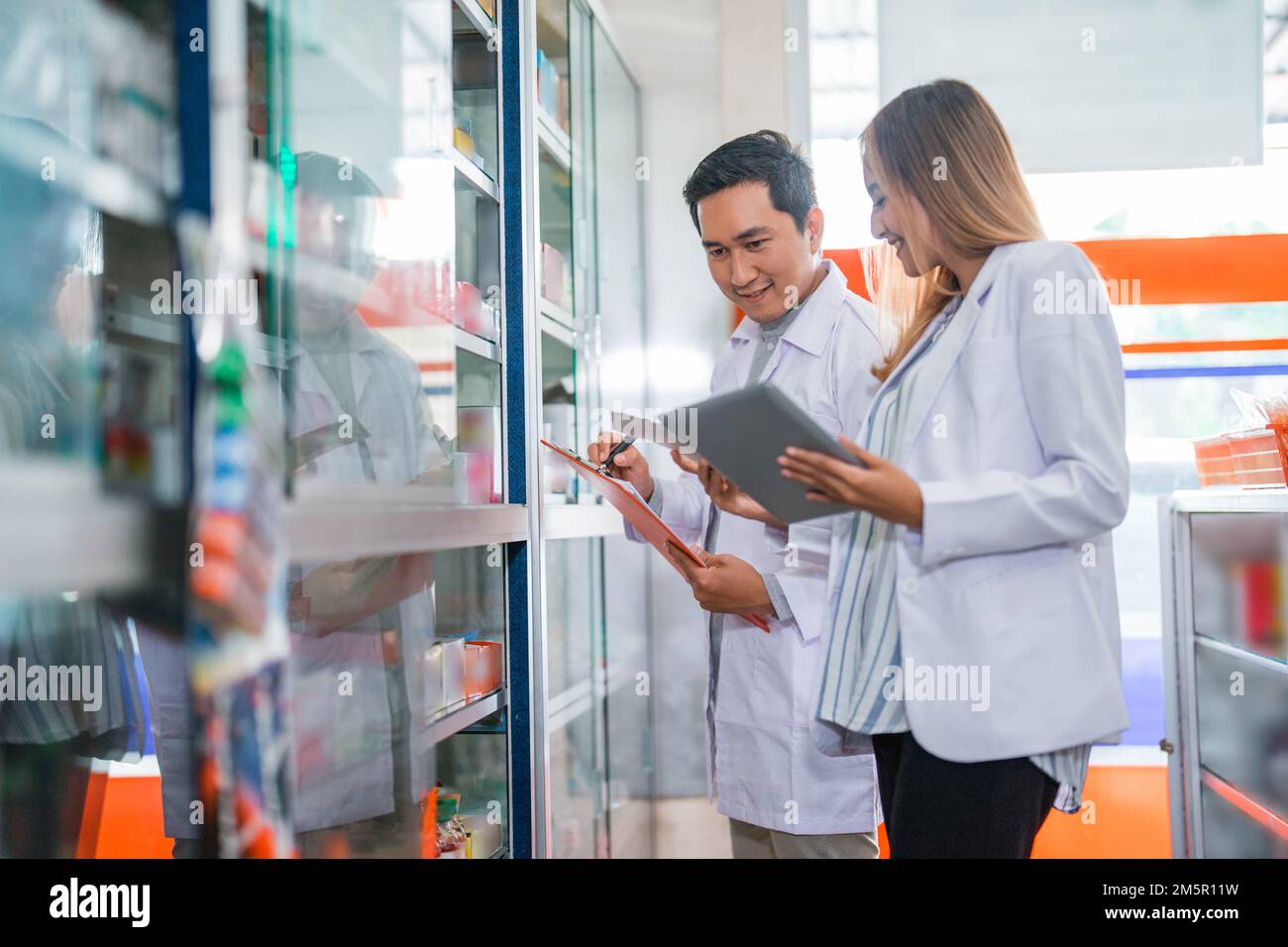 female pharmacist in uniform using pad while checking with friends ...