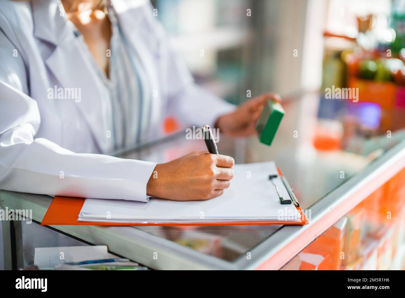 close up of pharmacist working writing drug list with pen and clipboard ...