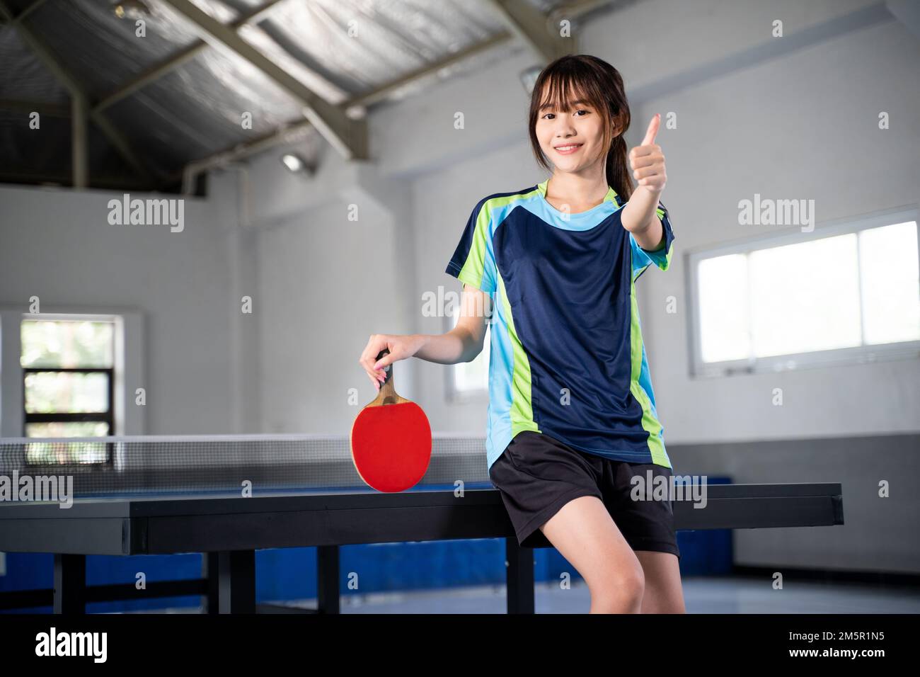 Female player holding red ping pong paddle with thumbs up Stock Photo ...