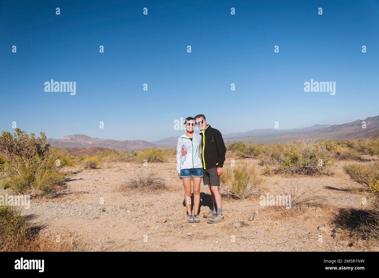 a bi-racial happ couple within the desert landscape of joshua tree ...