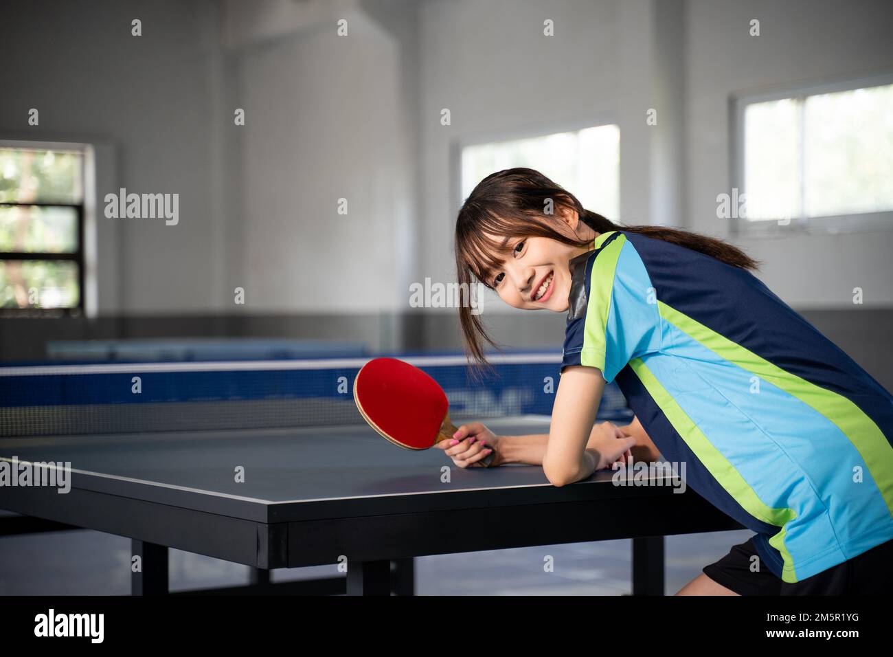female athlete smiling while leaning on ping pong table Stock Photo - Alamy