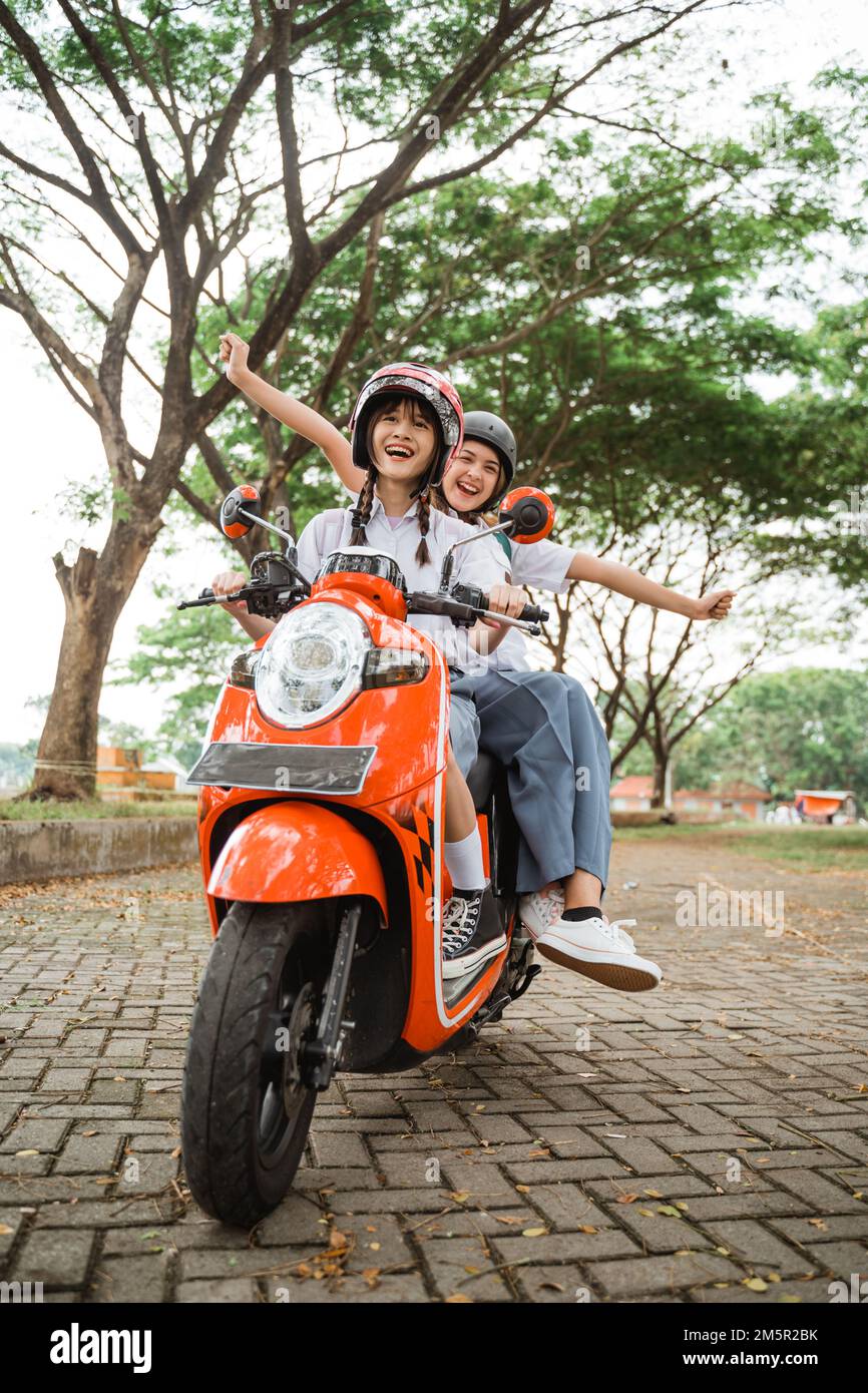 Two happy friends wearing helmets celebrating while riding a motorcycle ...