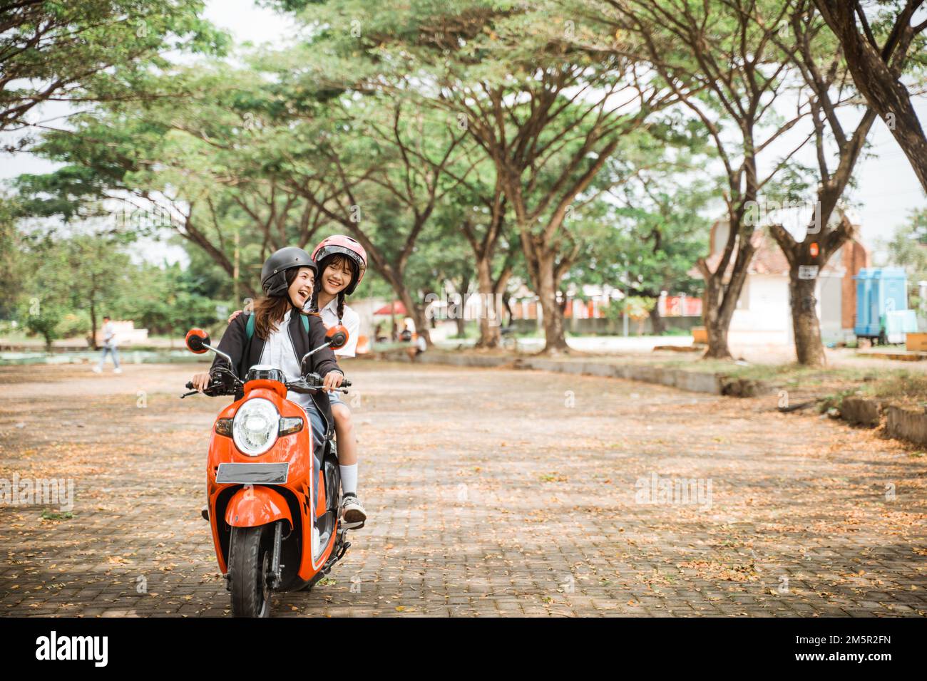 Two high school girls go to school together on motorbike Stock Photo ...