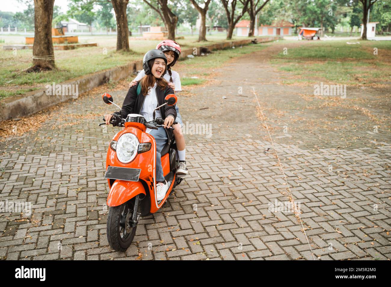 Two high school student girls enjoying riding a motorbike Stock Photo ...