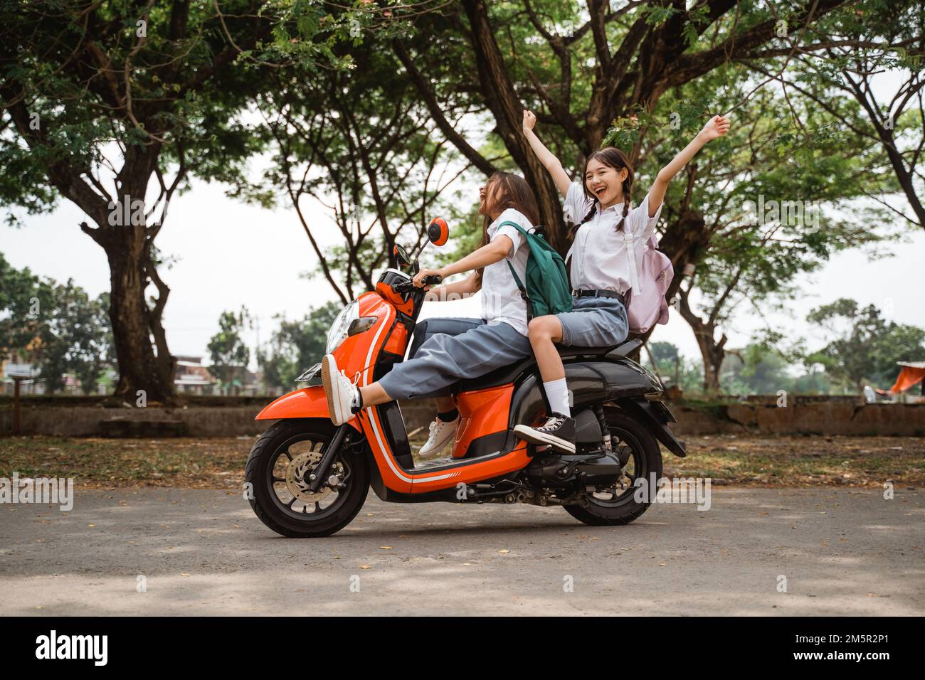 Two naughty high school girls riding motorbikes waving hands Stock ... Two naughty high school girls riding motorbikes waving hands Stock ...
