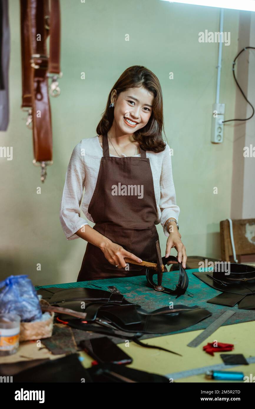 female craftswoman smiles while smoothing of the tanned leather Stock ...