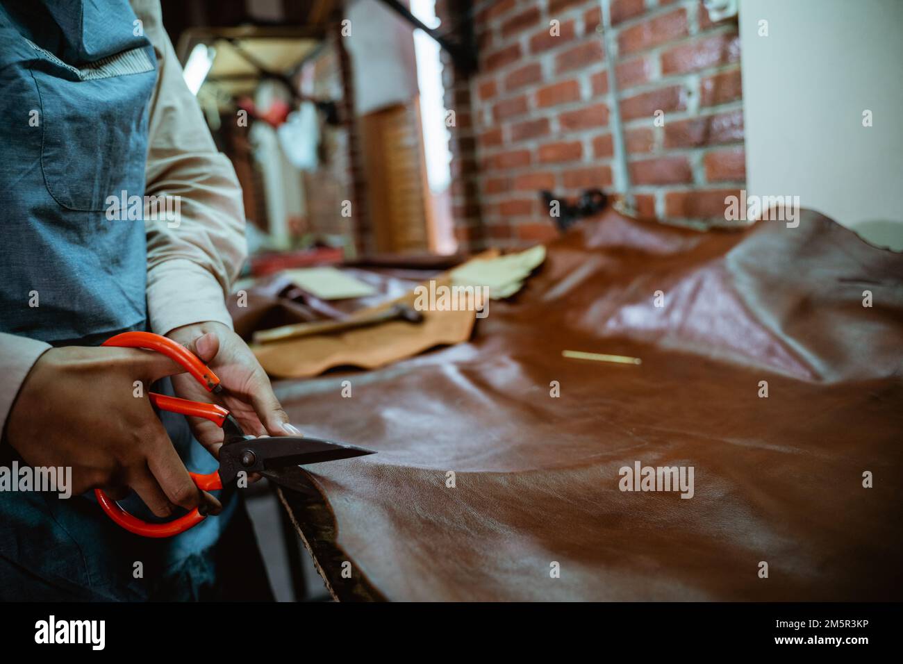 Hands of craftswoman cutting at table in leather fabric Stock Photo - Alamy