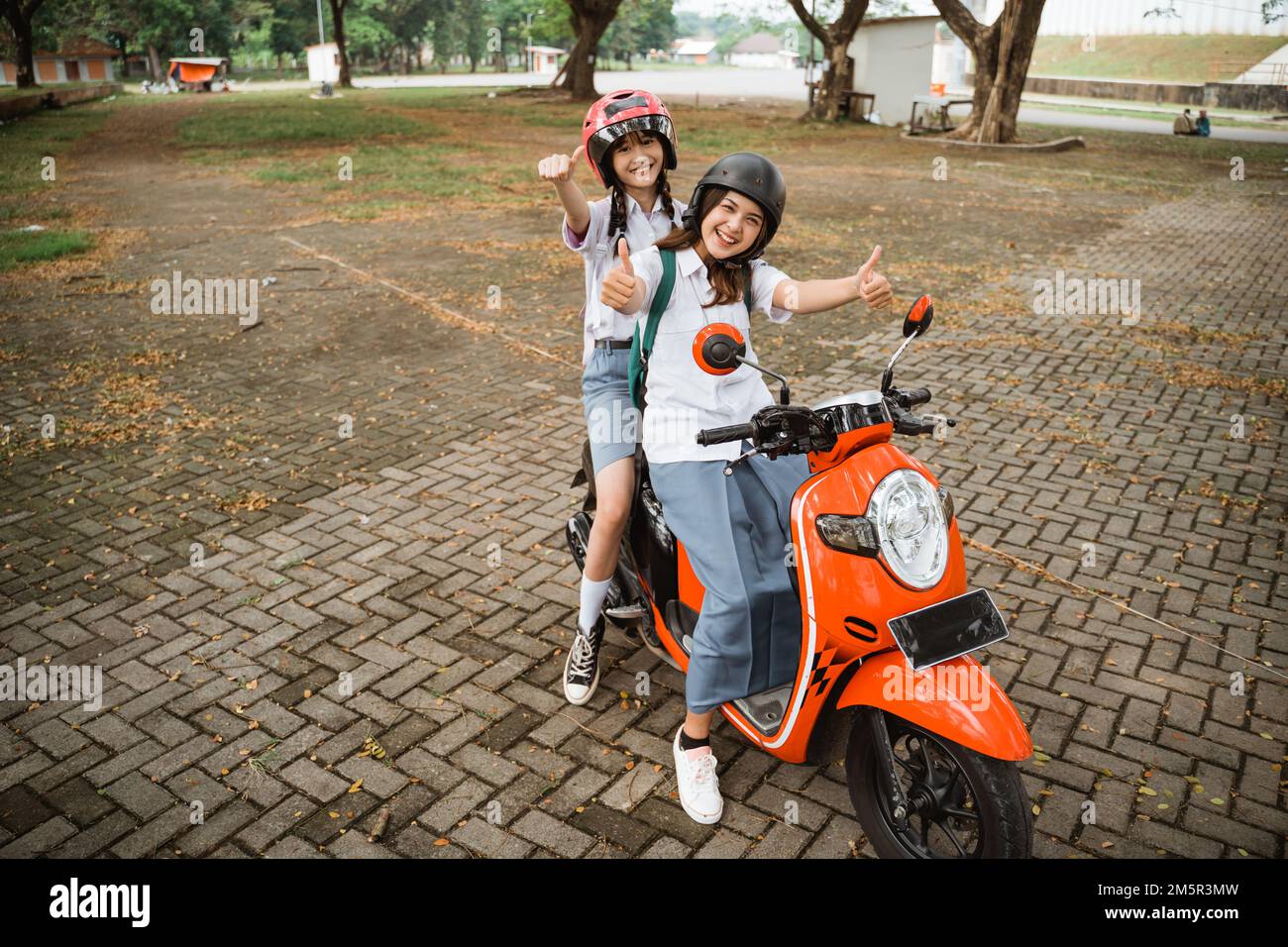 Two asian student girls wearing helmets with thumbs up Stock Photo - Alamy