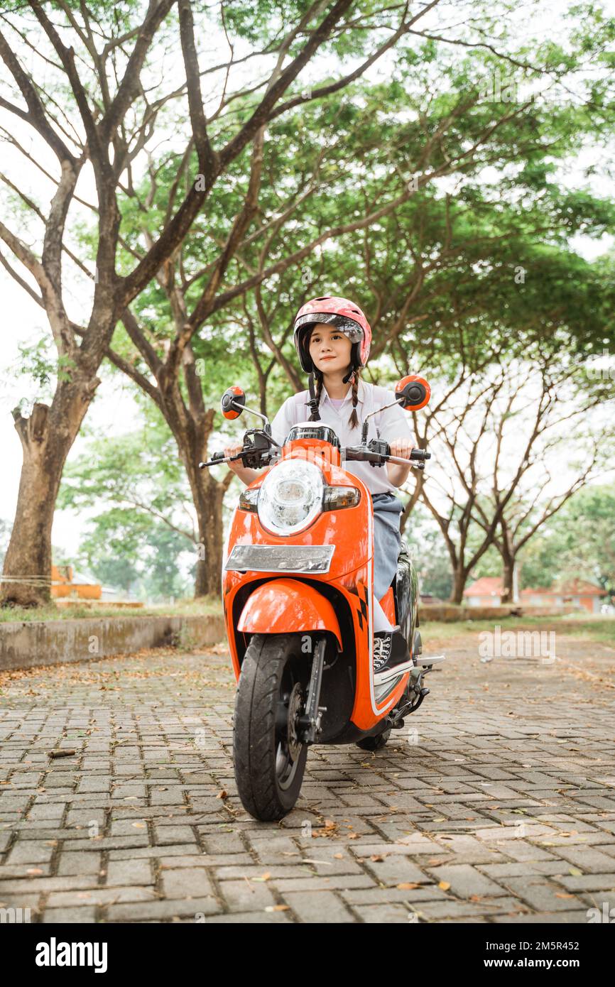 student girl is careful riding a motorcycle wearing a helmet Stock ...