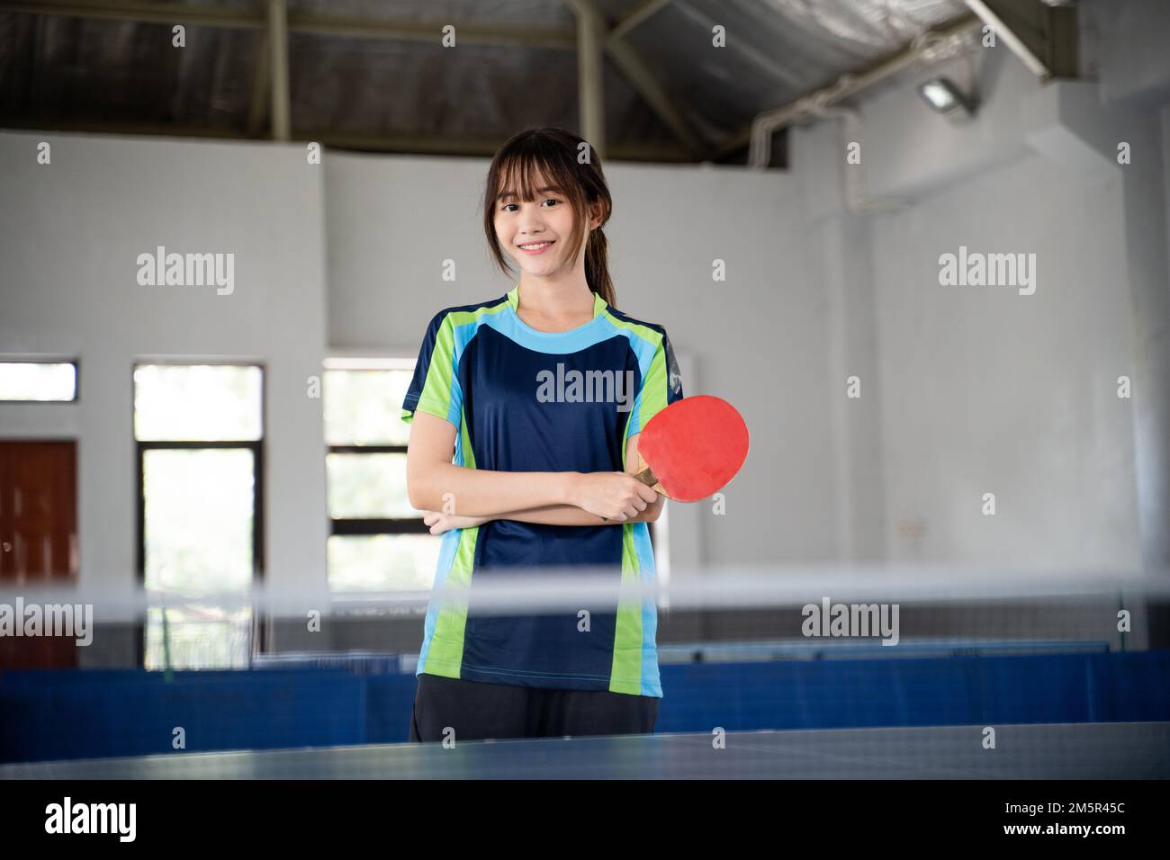 Female table tennis player holding paddle with arms crossed Stock Photo ...