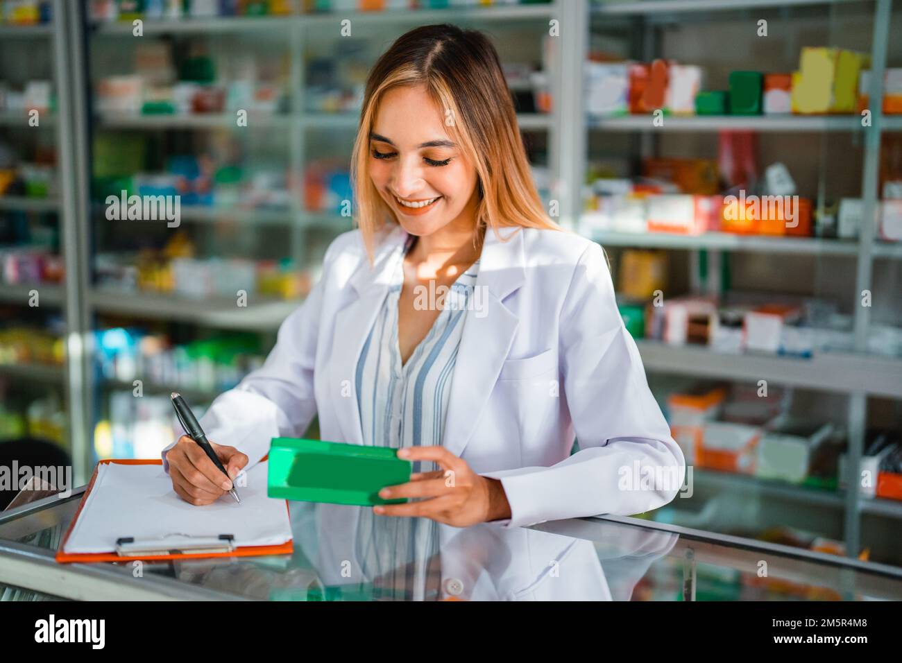 female pharmacist working writing drug list with pen and clipboard ...