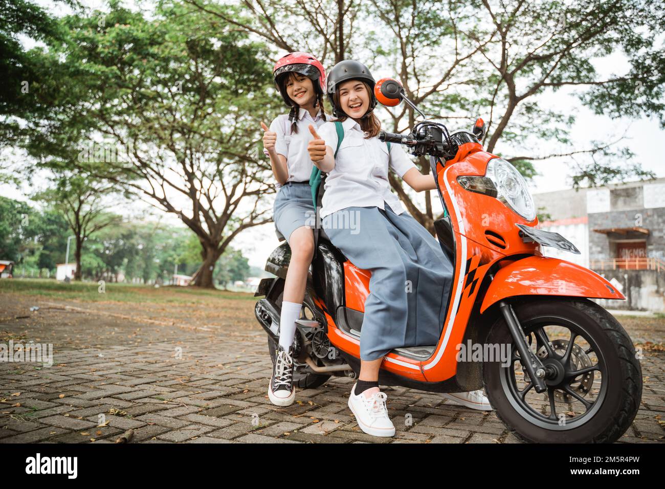 Bottom view of two girls wearing helmets with thumbs up Stock Photo - Alamy