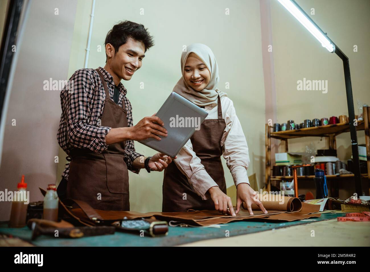 female craftsmen in hijab with male craftsman using a tablet Stock ...