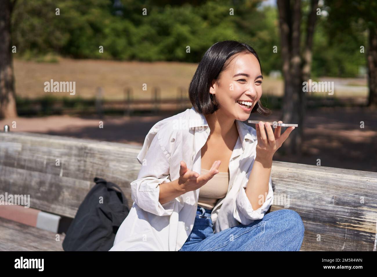 Portrait of happy asian girl records voice message, talking via ...
