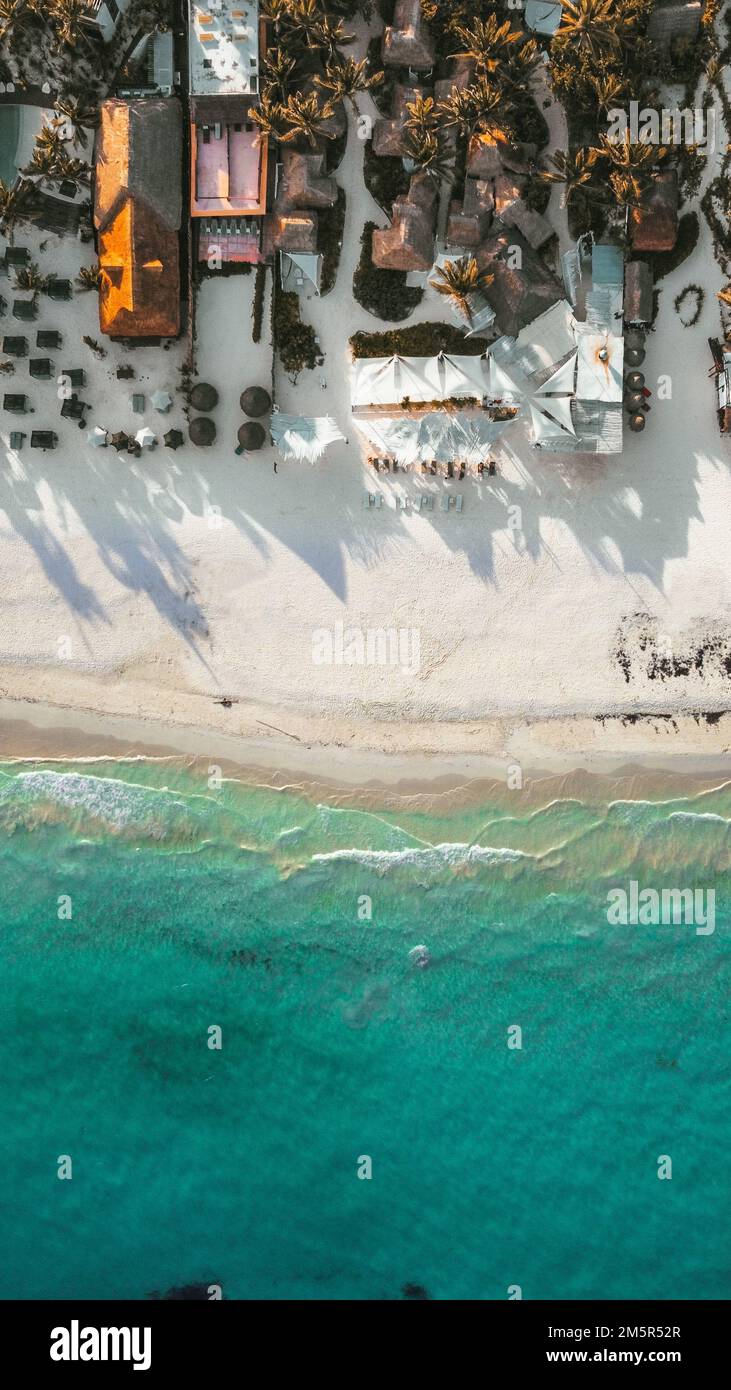 An aerial drone view of foamy waves crashing on a white sandy beach on ...