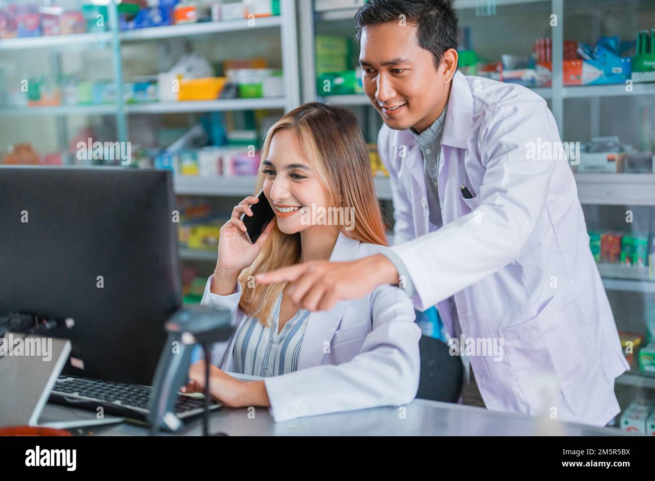 female and male pharmacists receiving phone calls while serving ...